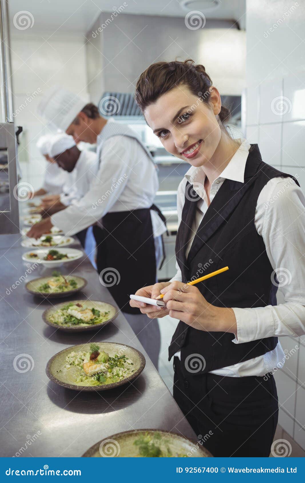 Smiling Waitress with Note Pad in Commercial Kitchen Stock Photo ...