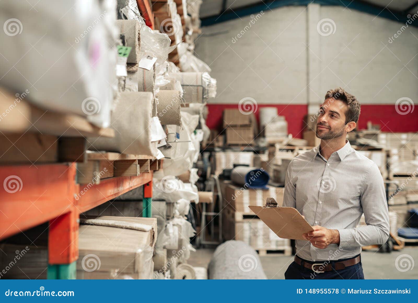 Smiling Warehouse Manager Using a Clipboard while Doing Inventory Stock ...