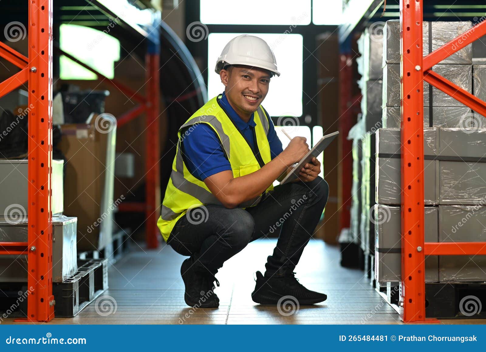 Smiling Warehouse Worker Sitting in Aisle between Rows of Tall Shelves ...