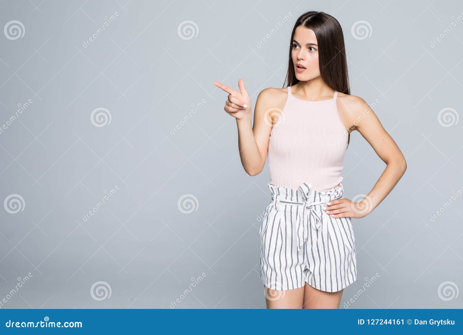 Smiling Woman Pointing Finger Side Isolated Portrait on Gray Background ... Smiling Woman Pointing Finger Side Isolated Portrait on Gray Background ...