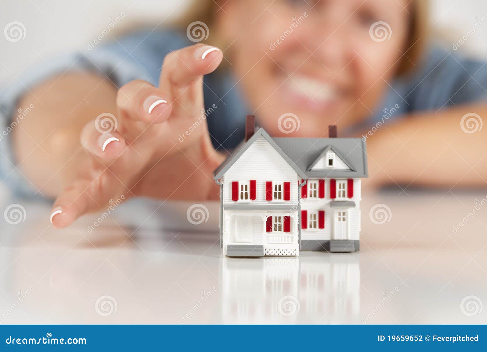 Smiling Woman Reaching for Model House on White Stock Photo - Image of ...