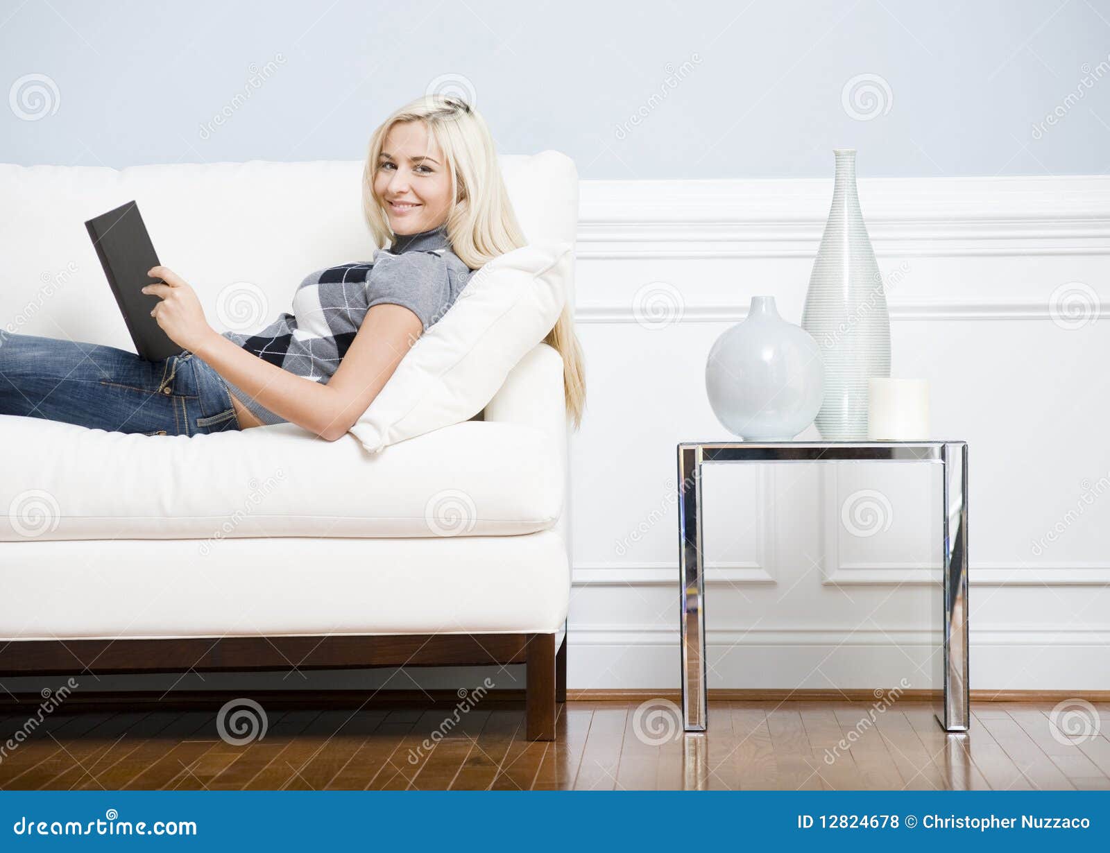 Smiling Woman Reclining on Couch with a Book Stock Photo - Image of ...