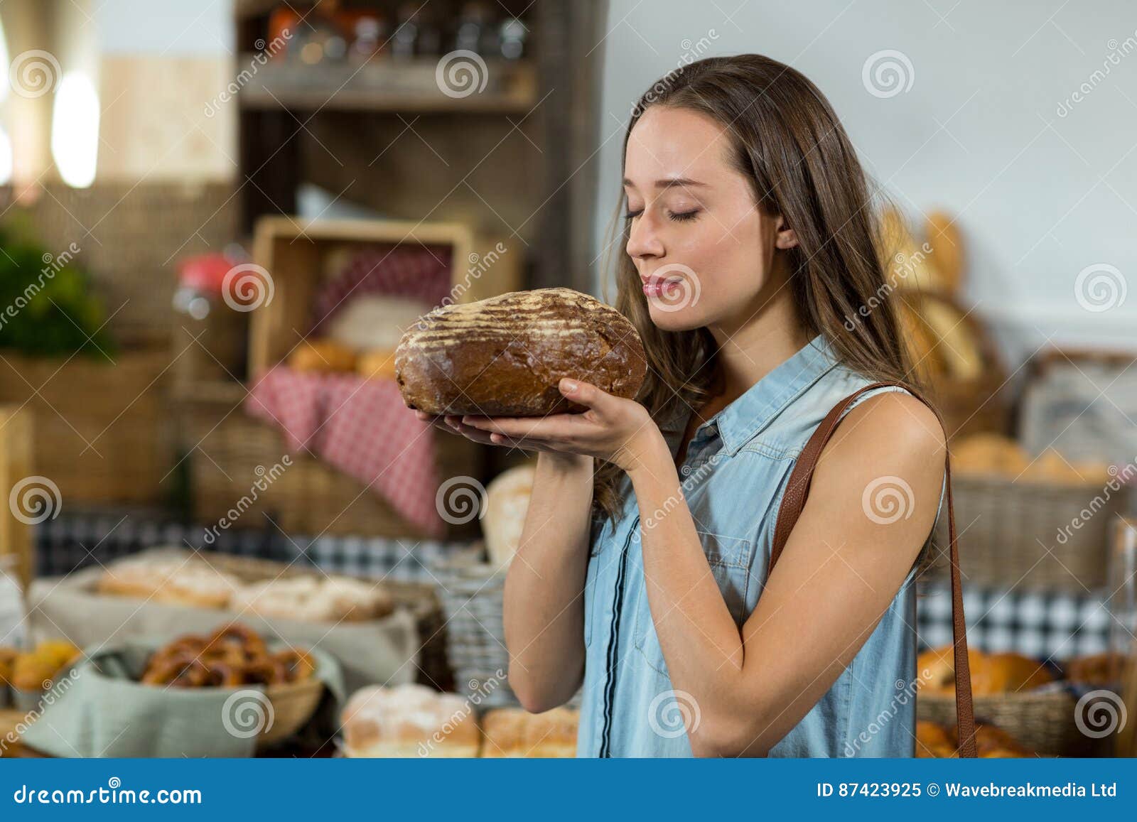 Smiling Woman Smelling a Round Loaf of Bread at Counter Stock Image ...
