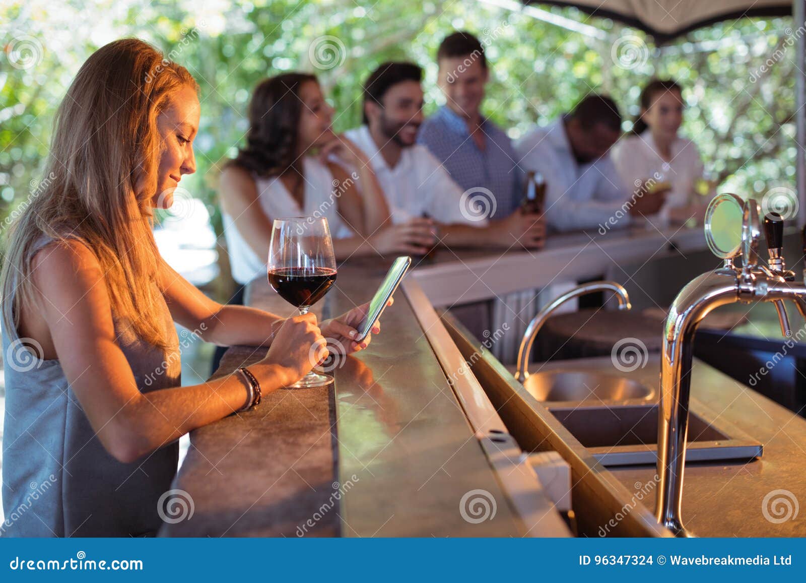 Smiling Woman Using Mobile Phone while Having a Glass of Wine Stock ...