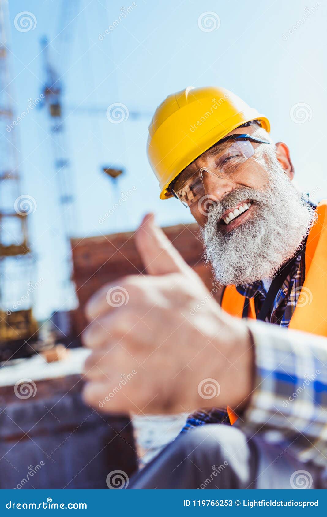 Smiling Worker in Reflective Vest and Hardhat Sitting at Construction ...