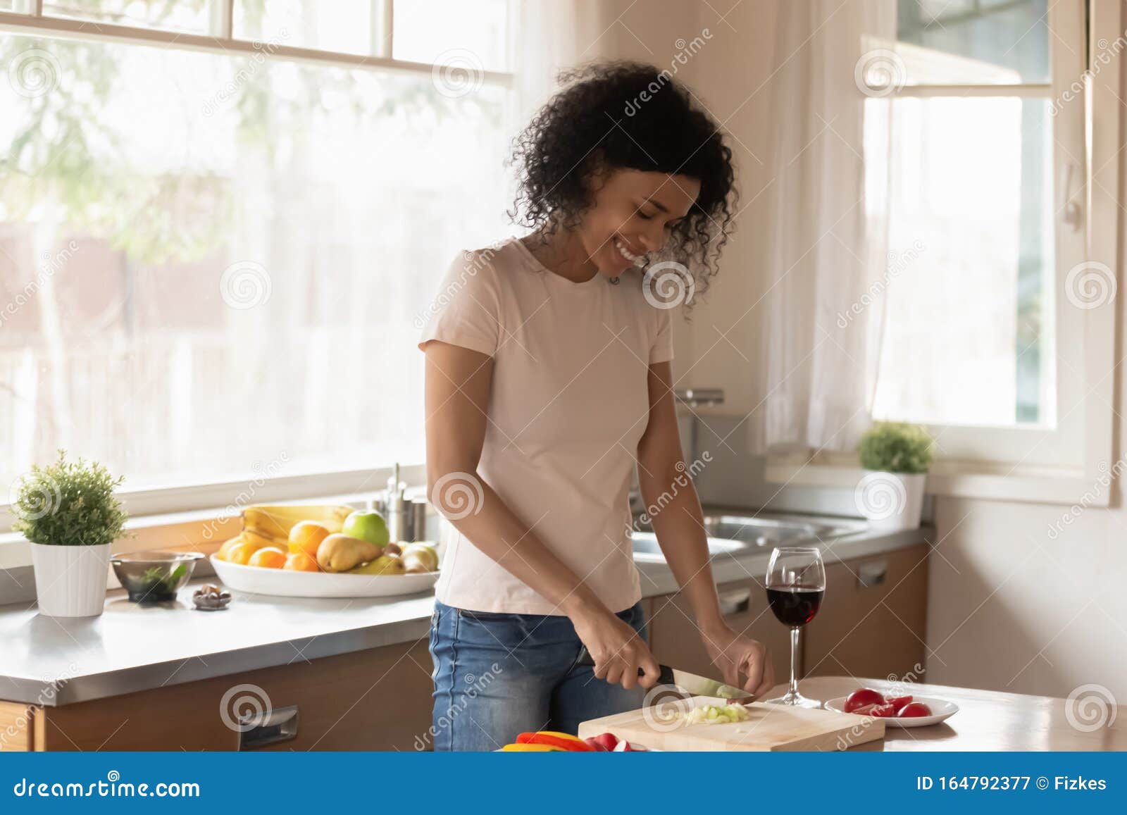 Smiling Biracial Woman Cooking Food In Modern Kitchen Stock Image