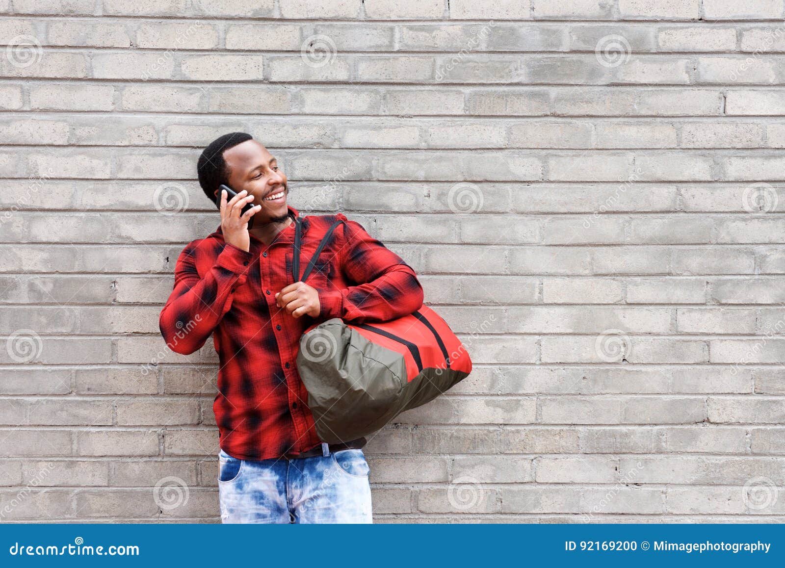 Smiling Young African Man Talking on Cellphone by Wall Stock Photo ...