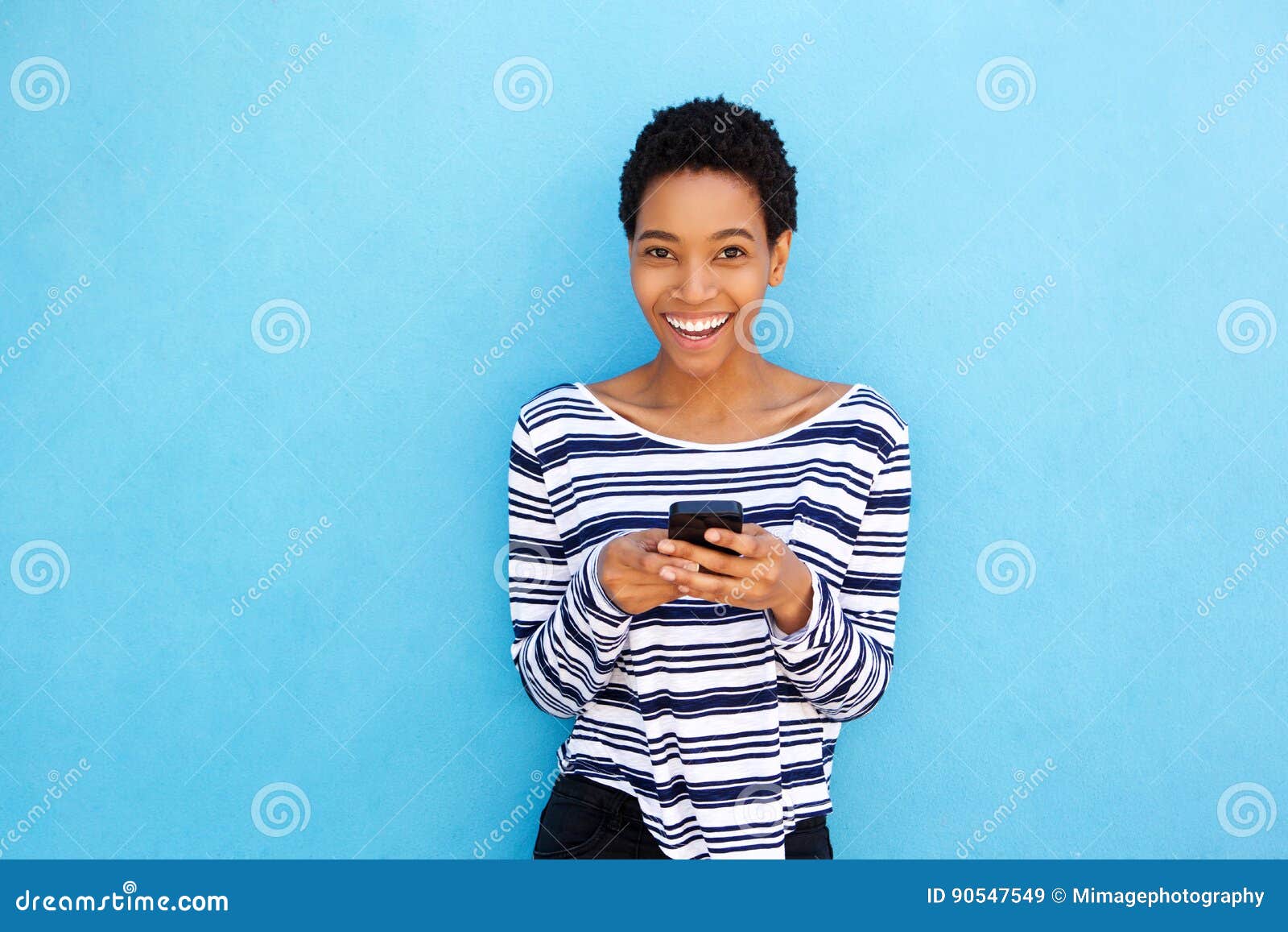 Smiling Young Black Woman Holding Cellphone by Blue Background Stock ... Smiling Young Black Woman Holding Cellphone by Blue Background Stock ...