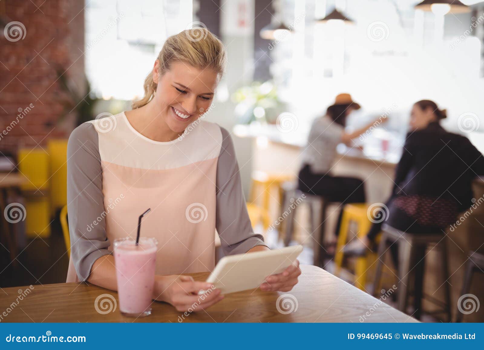 Smiling Young Blond Woman Using Tablet Computer while Sitting with ...