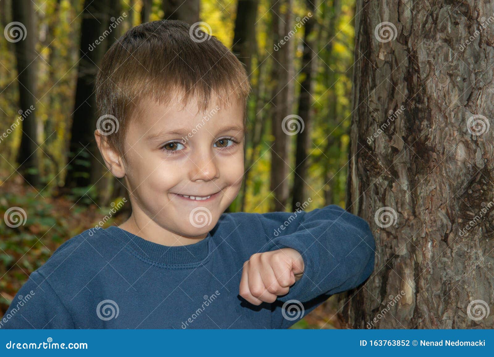 Smiling Young Boy Posing by Tree. Boy Posing Leaning Against a Tree in ...