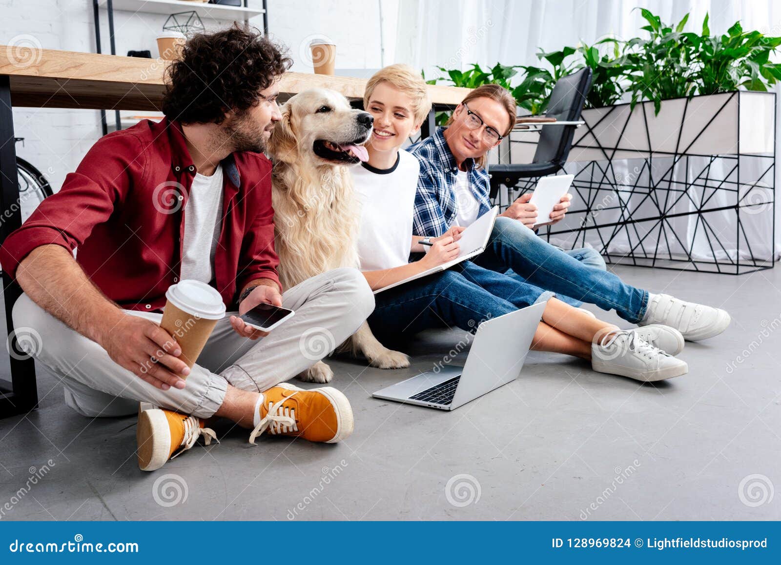 Smiling Young Business Colleagues Looking at Dog while Working Together ... Smiling Young Business Colleagues Looking at Dog while Working Together ...