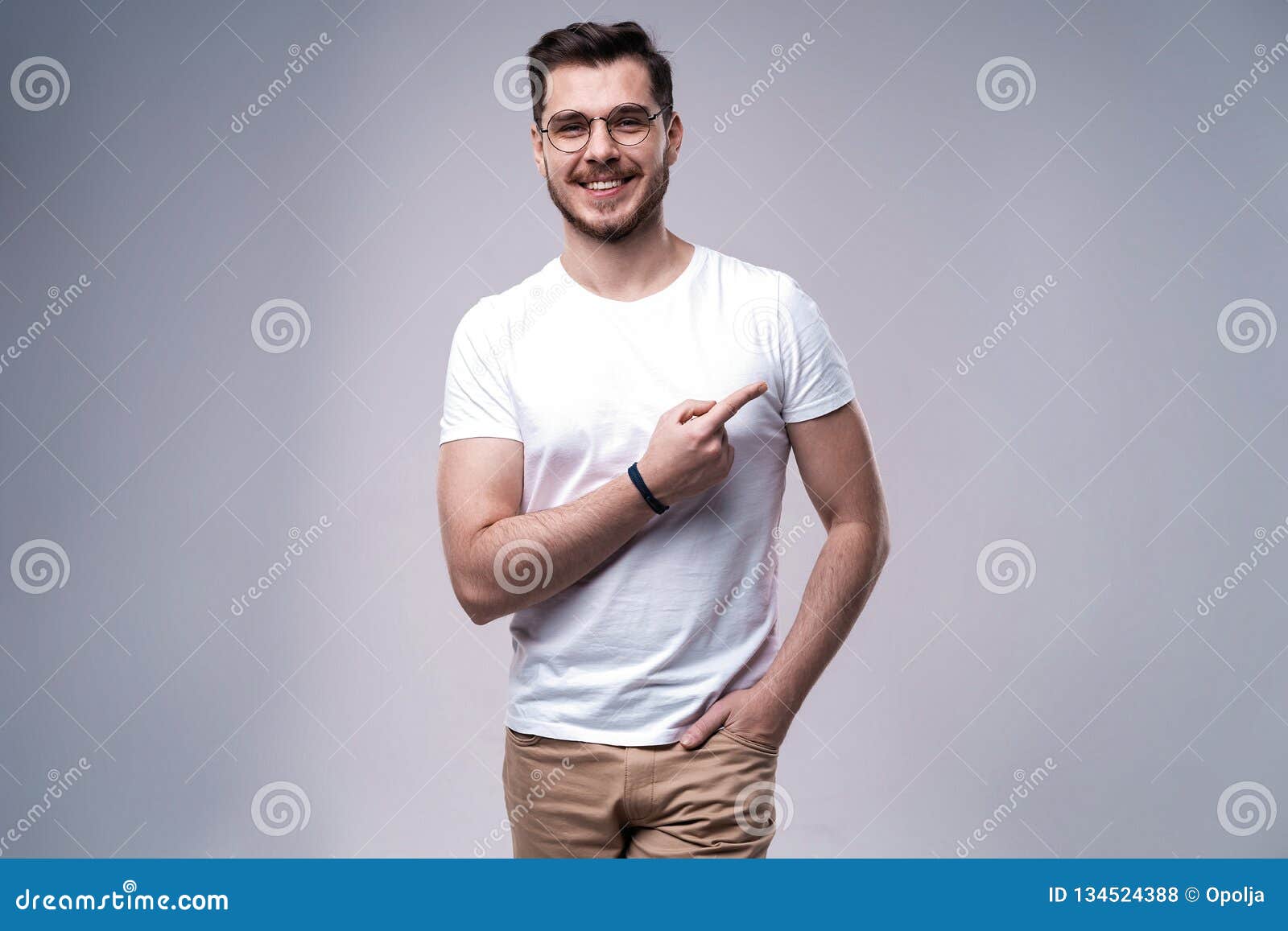 Smiling Young Casual Man Presenting Something on Gray Background. Stock ... Smiling Young Casual Man Presenting Something on Gray Background. Stock ...