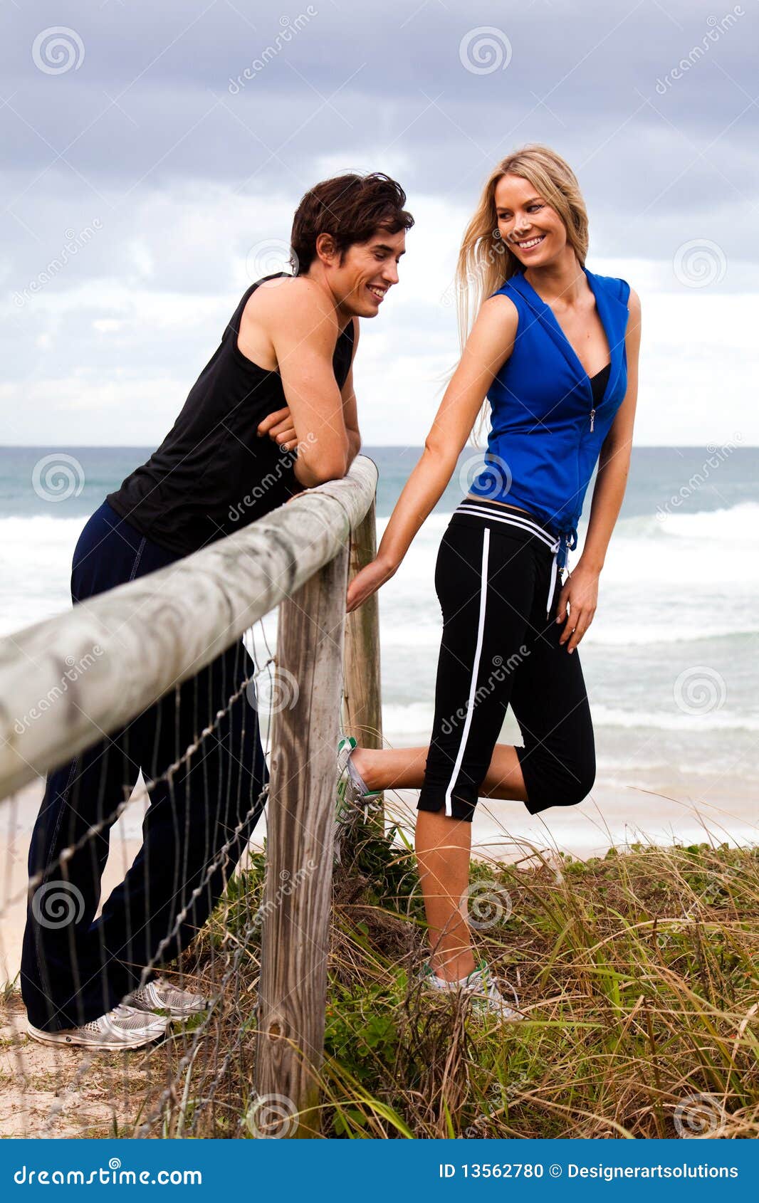 Smiling Young Couple by Fence at the Beach Stock Photo - Image of fence ...