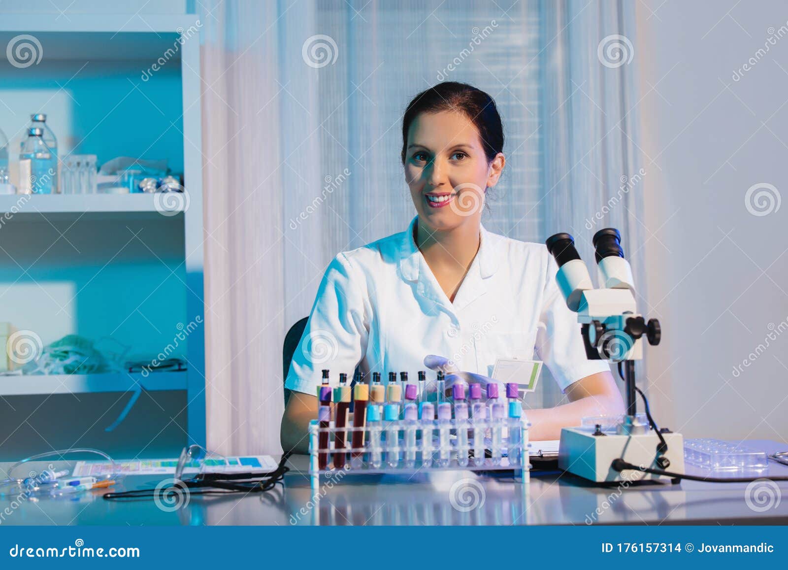 Young Female Scientist Using Microscope and Looking at Camera while ...