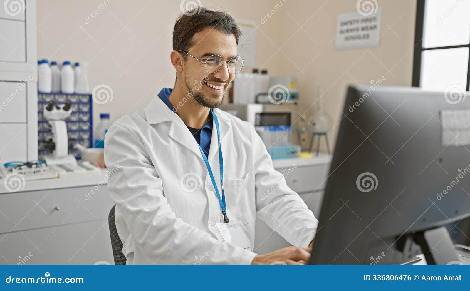 Smiling Young Hispanic Man with Beard in Lab Coat Using Computer in ...