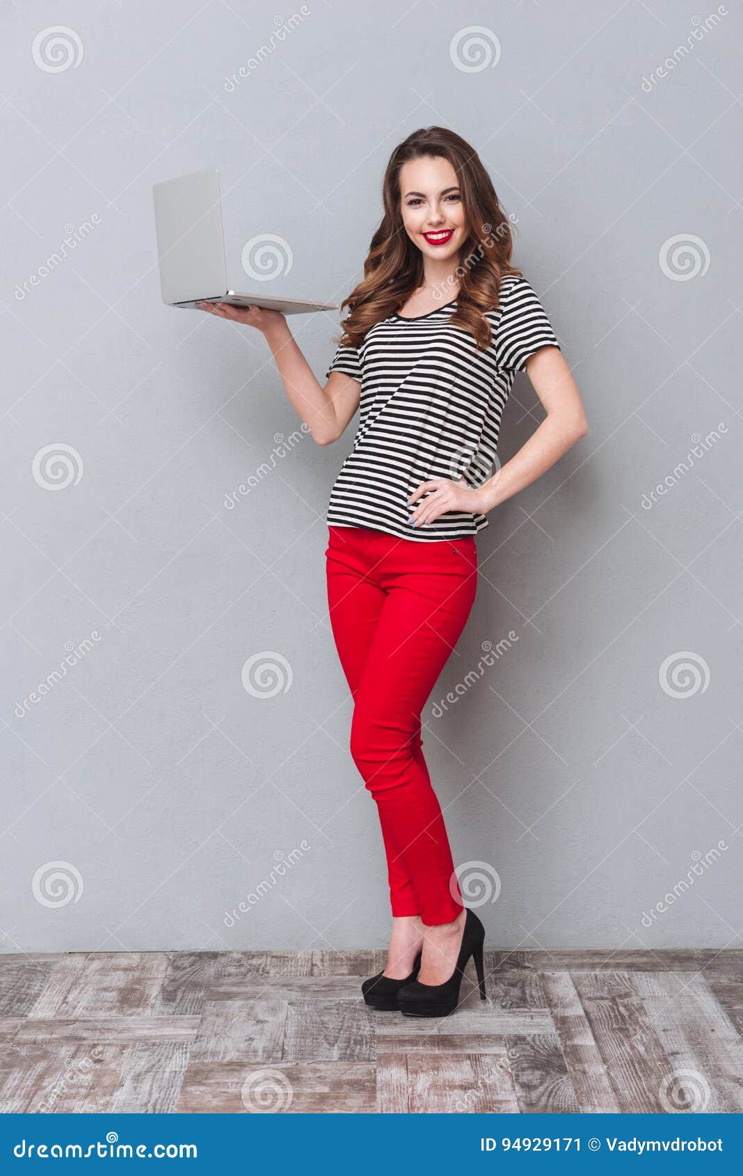 Smiling Young Lady Standing Over Grey Wall and Using Laptop Stock Image ...