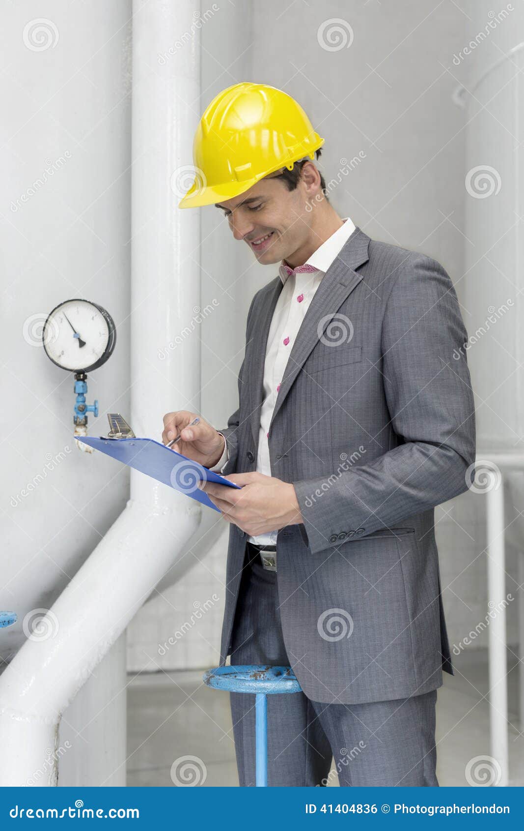Smiling Young Male Manager Writing on Clipboard in Industry Stock Photo ...