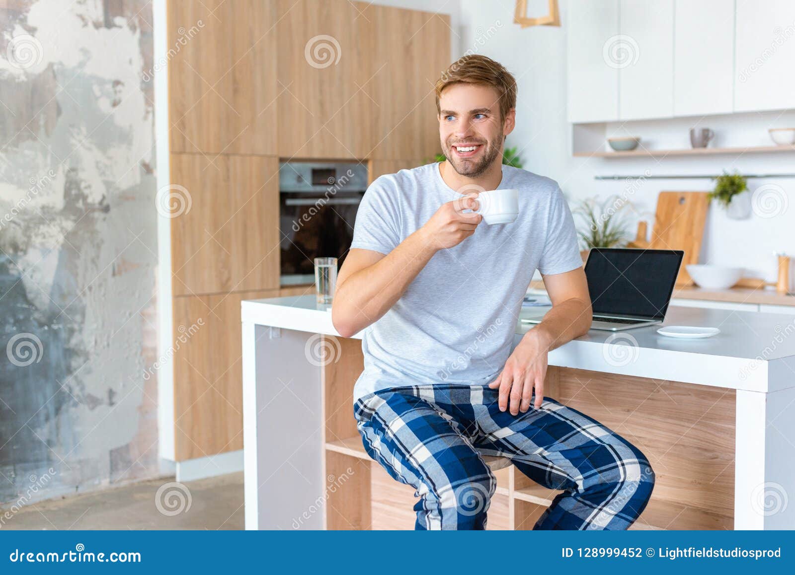 Smiling Young Man Drinking Coffee at Kitchen Table Stock Photo - Image ...