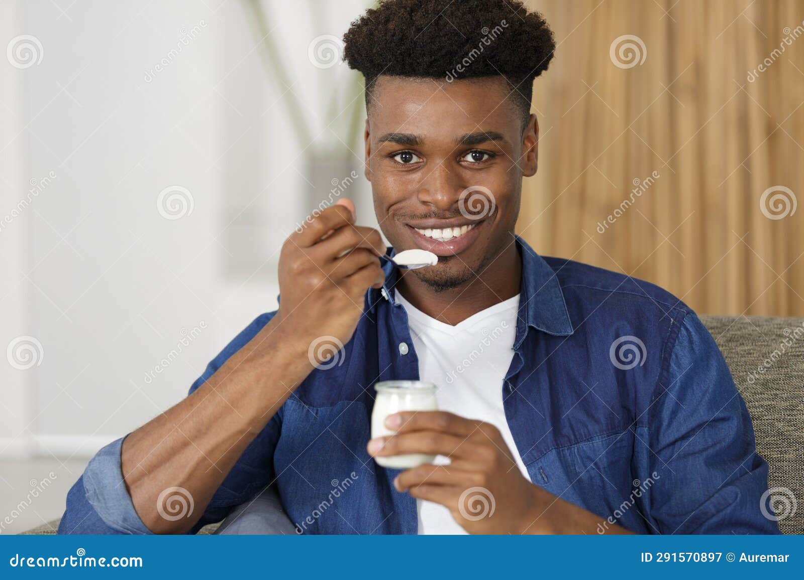 Smiling Young Man Eating Yogurt Stock Image - Image of indoor, cheerful ...