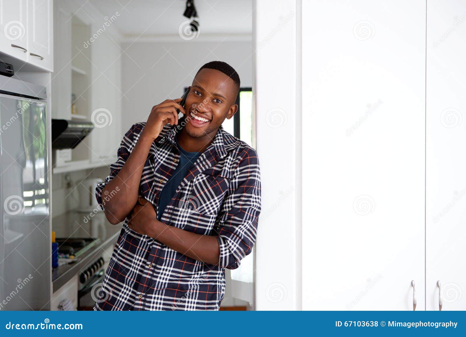 Smiling Young Man at Home Using Mobile Phone Stock Photo - Image of ...