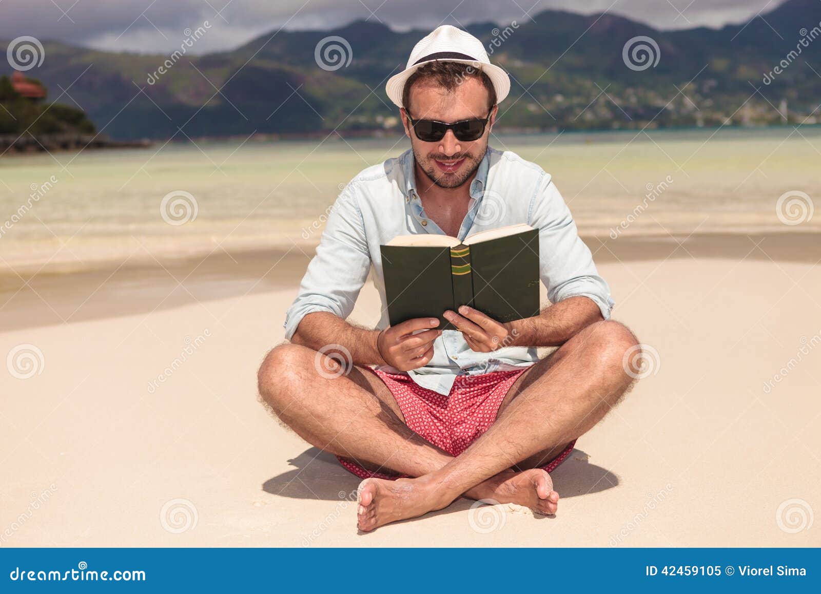 Smiling Young Man Reading a Book on the Beach Stock Image - Image of ...