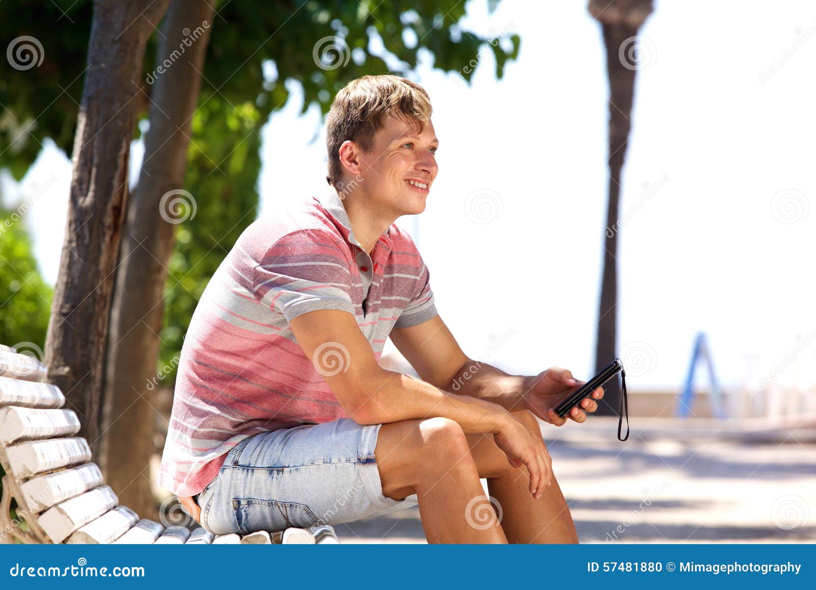 Smiling Young Man Sitting Outside with Mobile Phone Stock Photo - Image ...