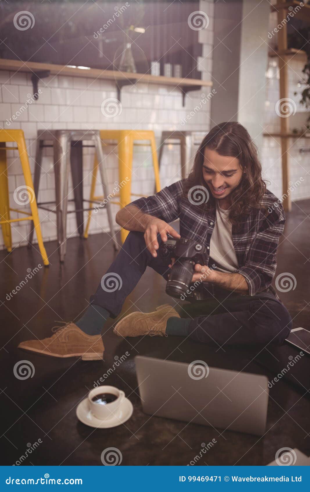 Smiling Young Man Using DSLR Camera while Sitting with Laptop on Floor ...