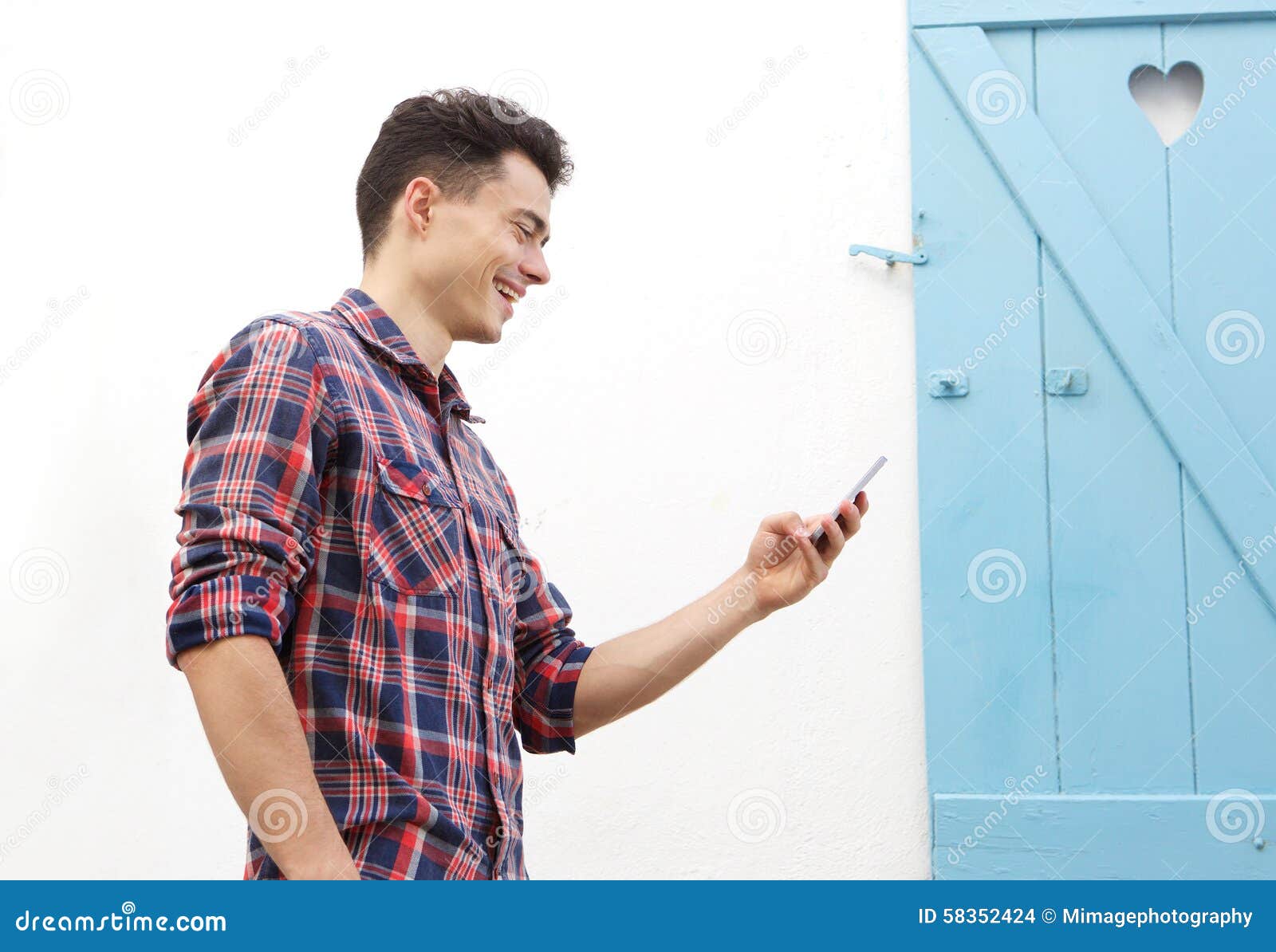 Smiling Young Man Walking Outside with Mobile Phone Stock Photo - Image ...