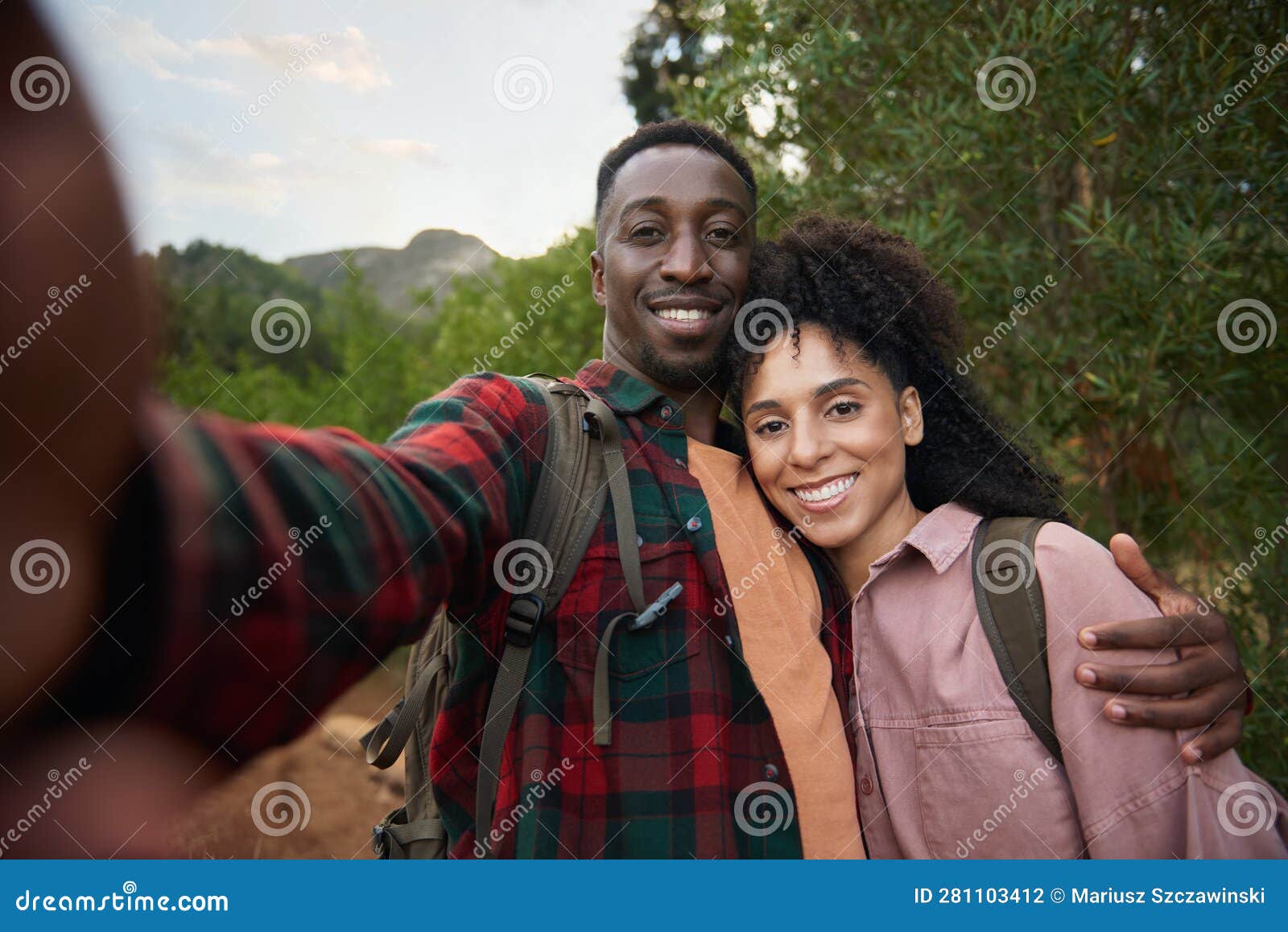 Smiling Young Multiethnic Couple Taking Selfies On A Hiking Trail Stock