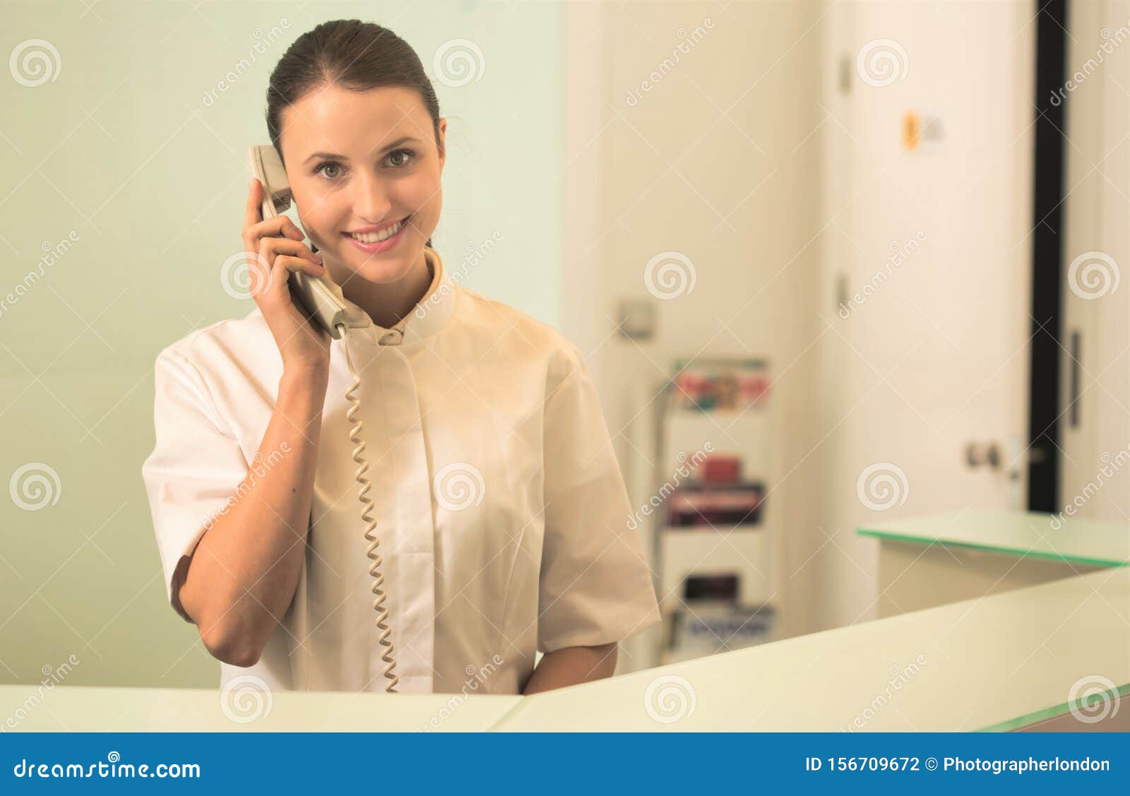 Smiling Young Receptionist Talking on Phone at Checkout Counter Stock ...