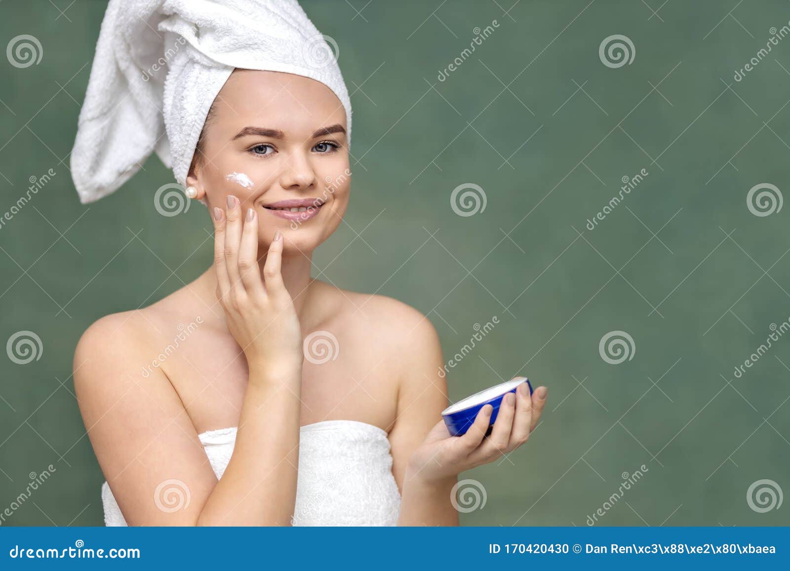 Smiling Young Woman Applying Moisturizer On Face For Healthy Skin Stock