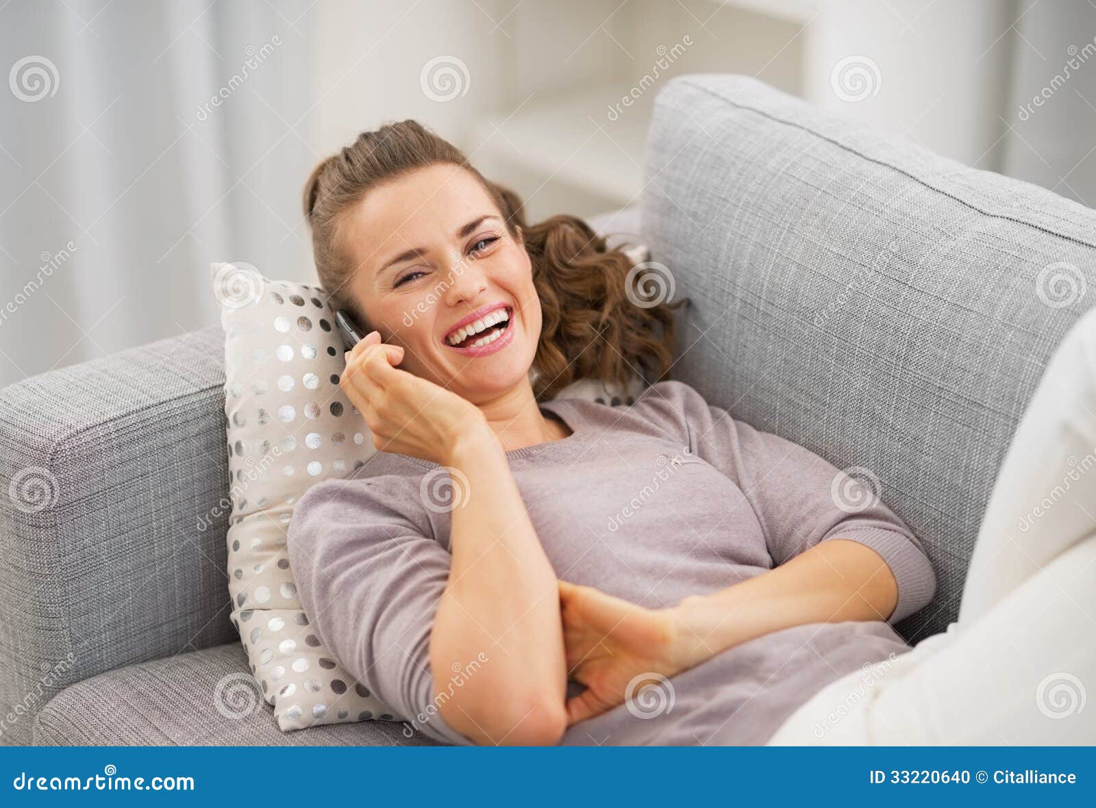 Smiling Young Woman Talking Mobile Phone while Laying on Couch Stock ... Smiling Young Woman Talking Mobile Phone while Laying on Couch Stock ...