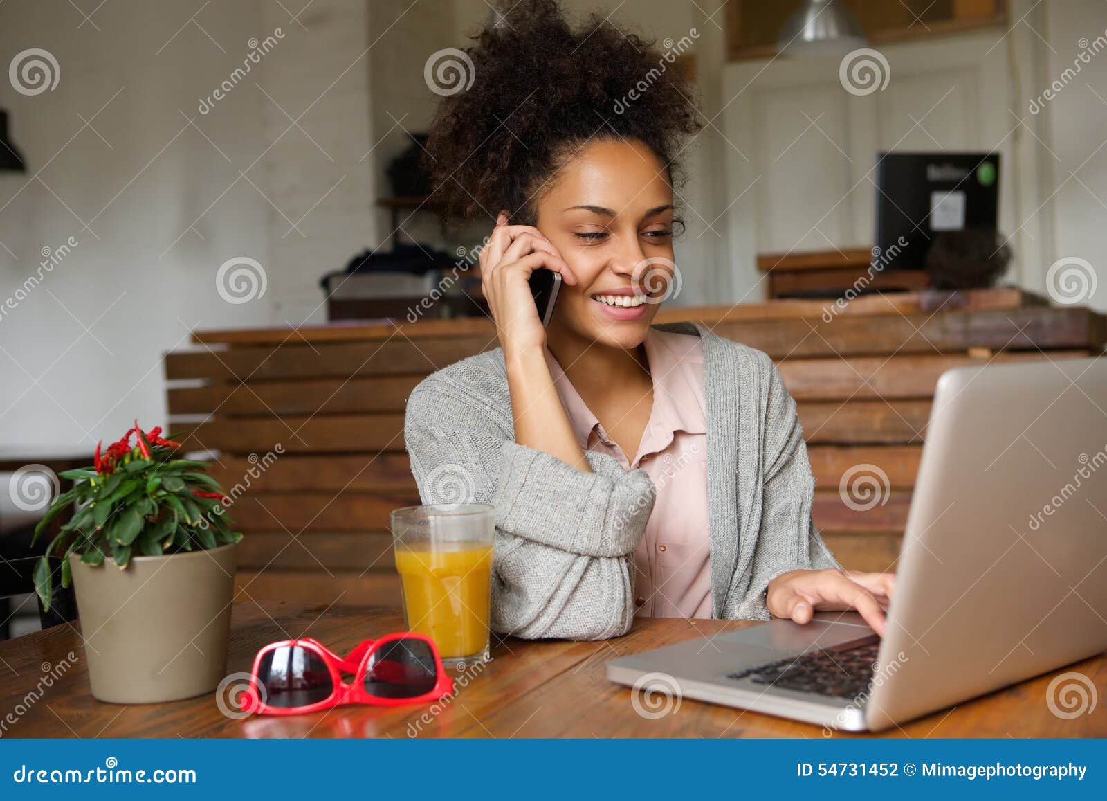 Smiling Young Woman Using Laptop and Talking on Mobile Phone Stock ...