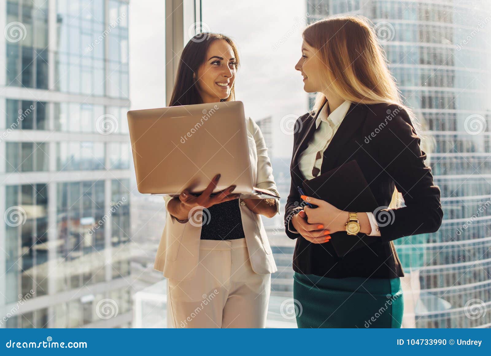 Smiling Young Women with Laptop Standing and Talking in Office Stock ...