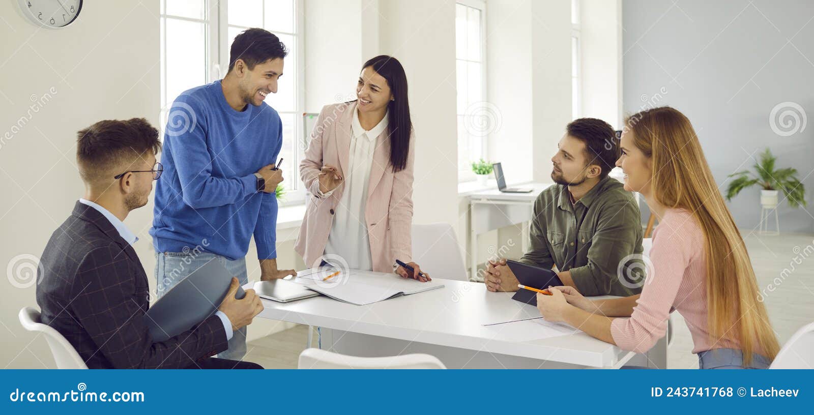 Smiling Young Workers Sitting at Office Desk, Talking and Discussing ...