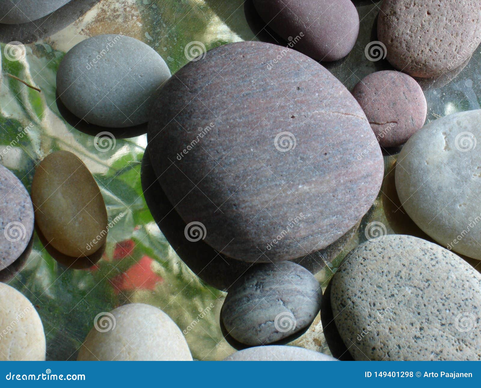 Red Flower Reflection Can Be Seen Under Smooth Rocks. Stock Photo ...