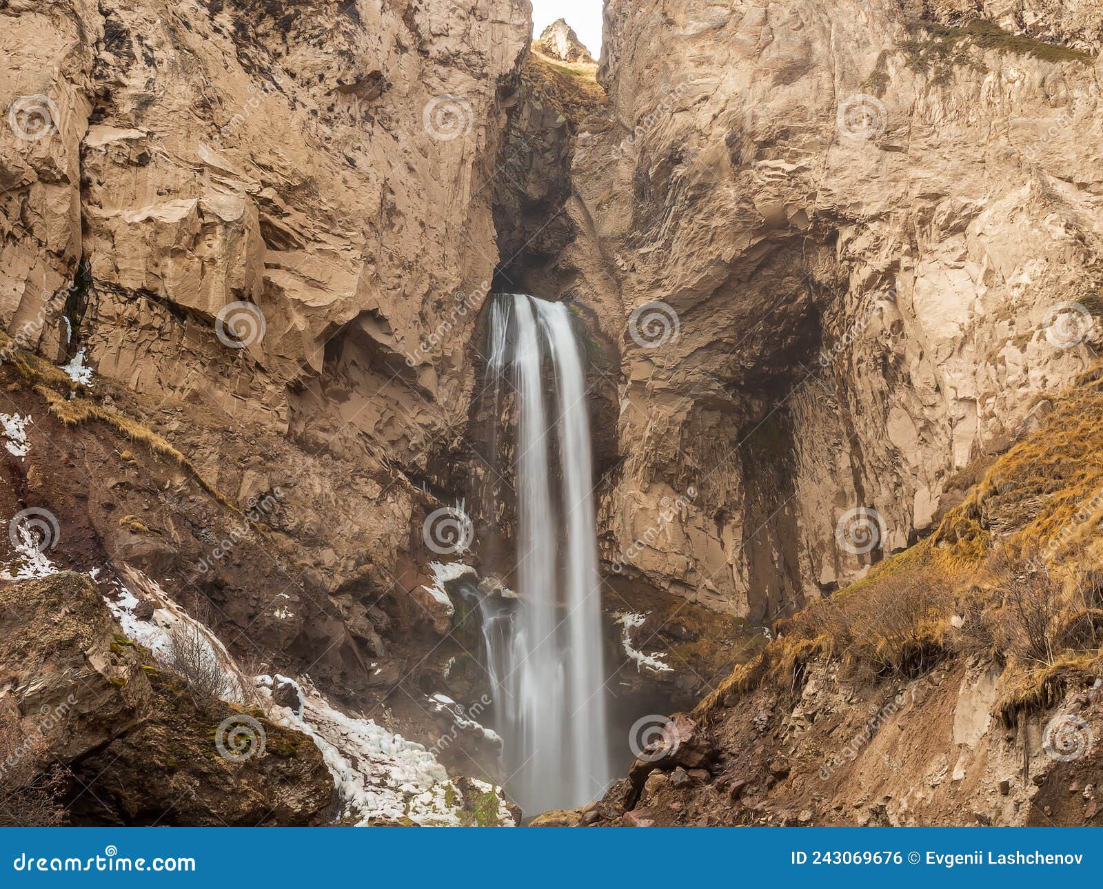 A Smooth Stream of Water Flows Down from a Cave in the High Rocks of ...