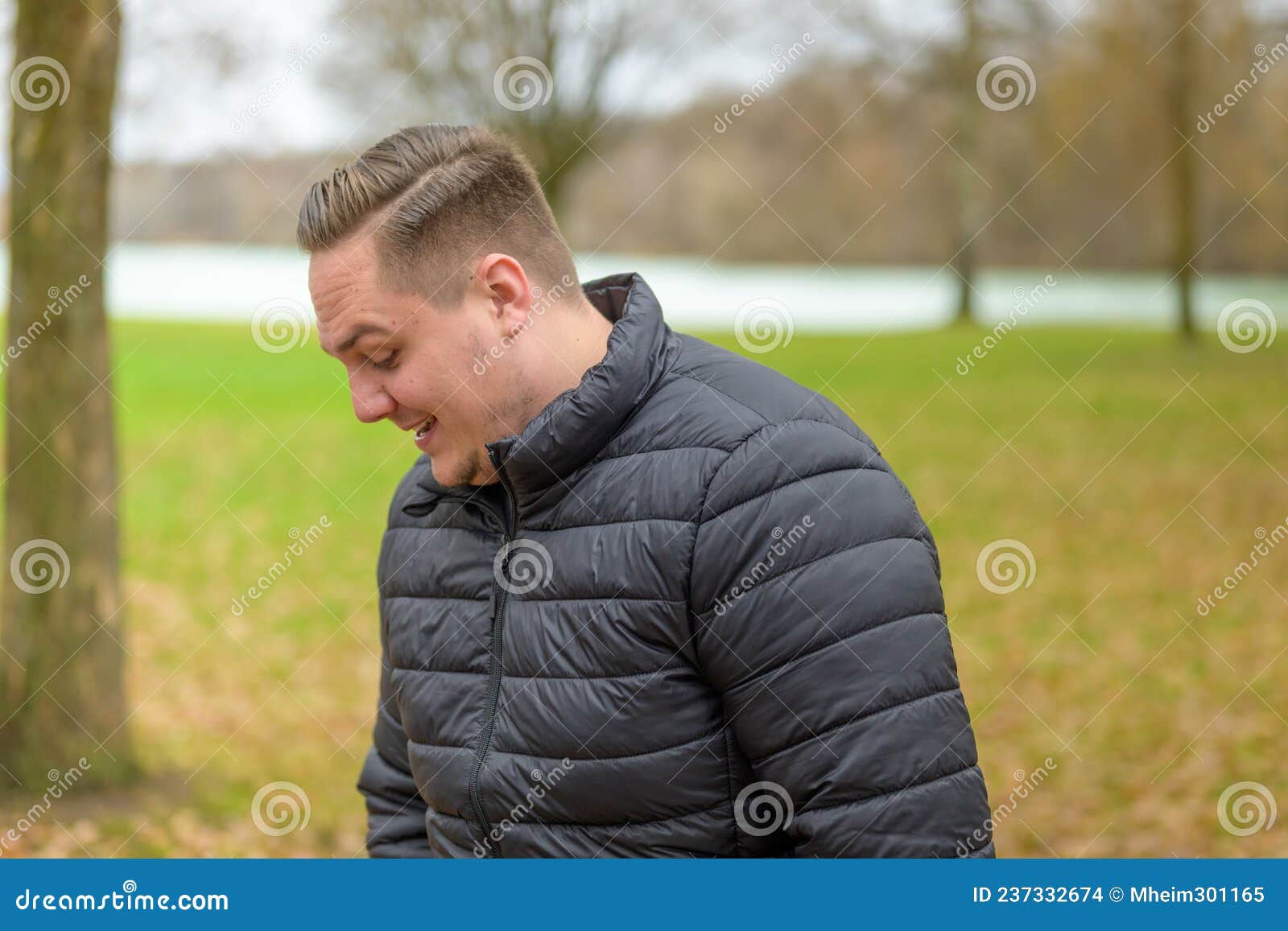 Sniggering Young Man Looking Down with a Smile Stock Photo - Image of park, garden: 237332674