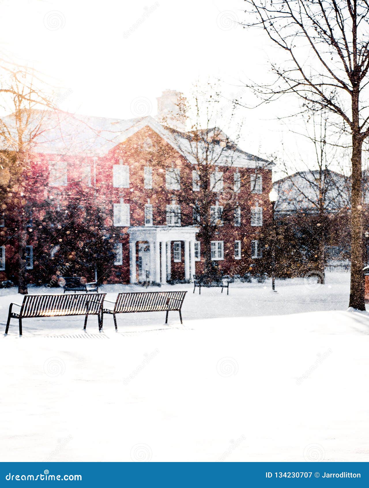 Snow Drift Falling in Front of a Brick Building with Sun Rays Peaking ...