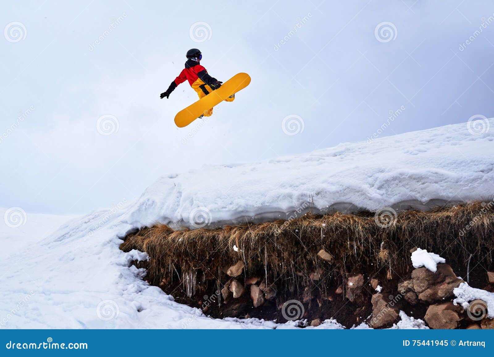 Snowboarder Jumping from Springboard on a Snowy Hill with Grass. Stock ...