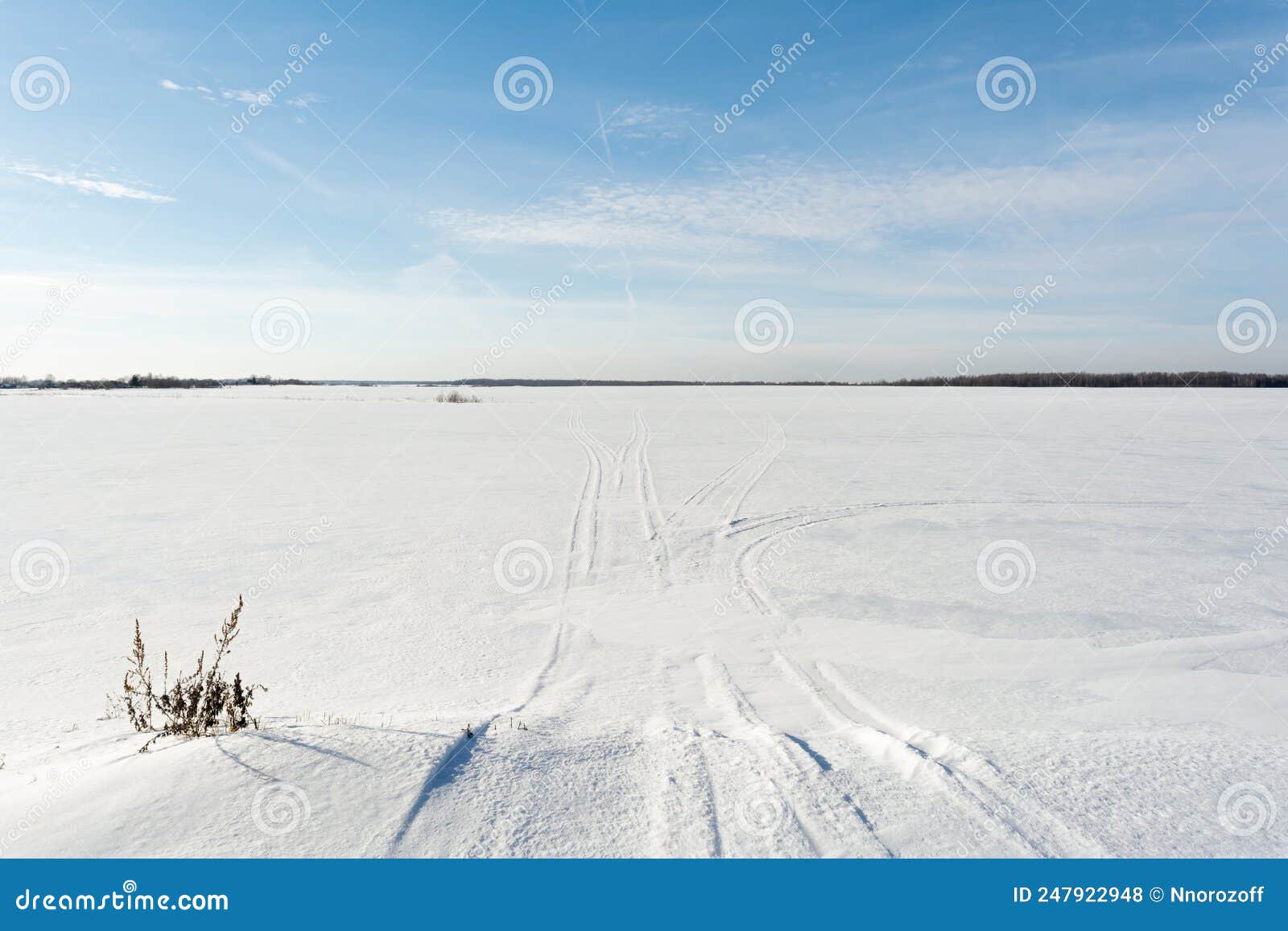 Snowmobile Tracks on a Winter Field. Sunny Winter Day with Blue Sky ...