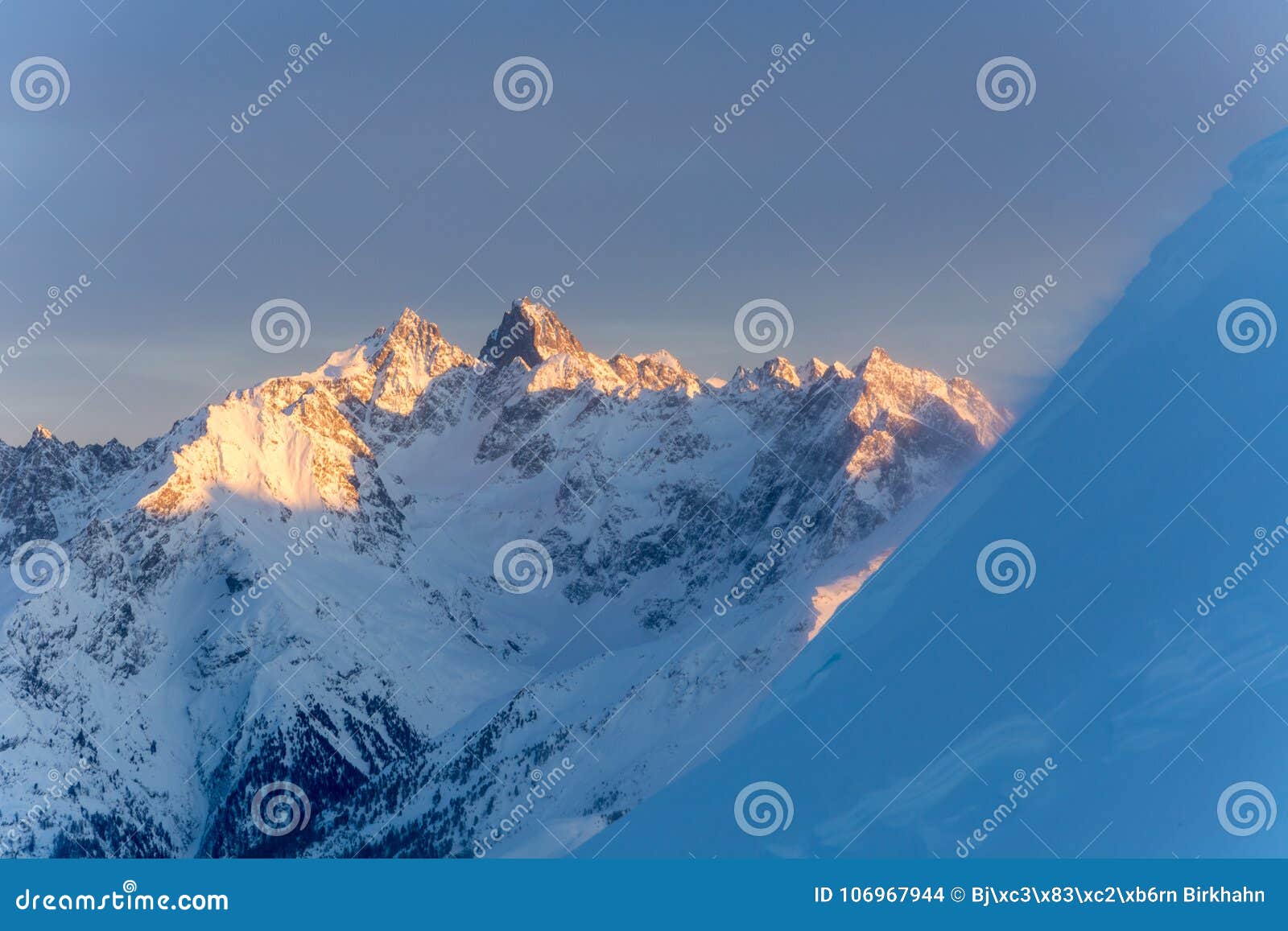 Snowy Mountains during Sunset with Snow Blowing Over the Edge Stock ...