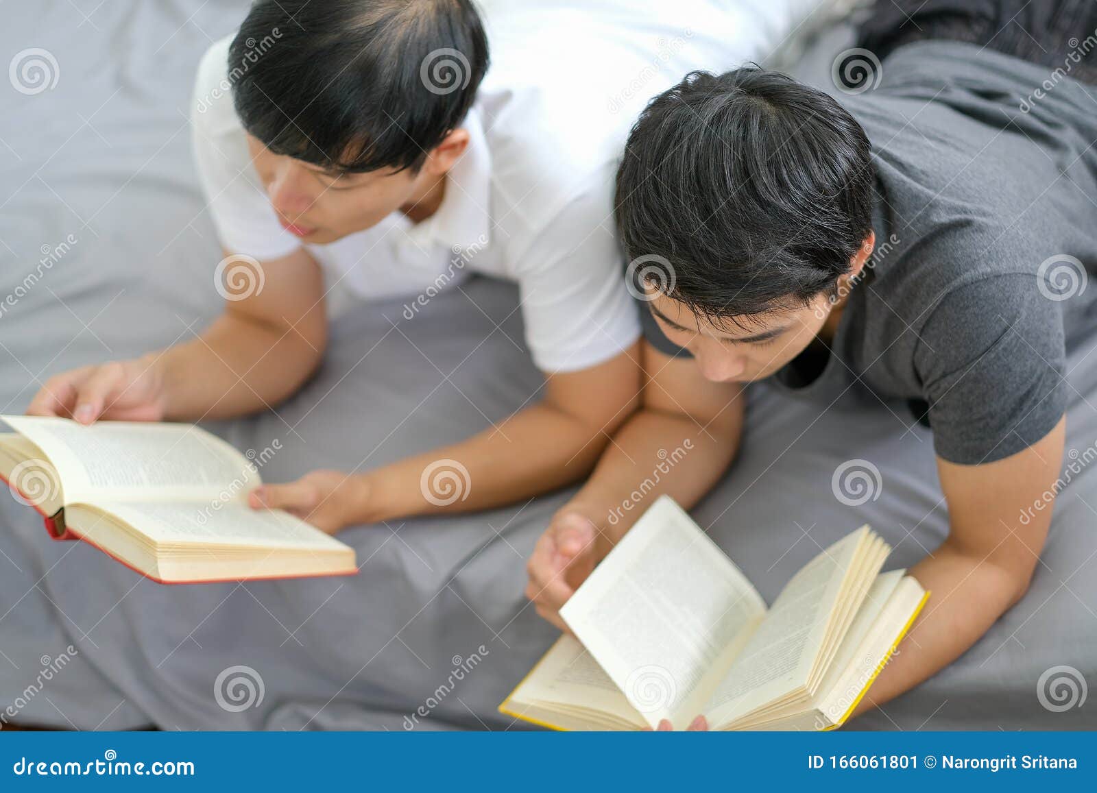 Soft Blur of Two Guys Read Some Books Together on Bed and they Look ...