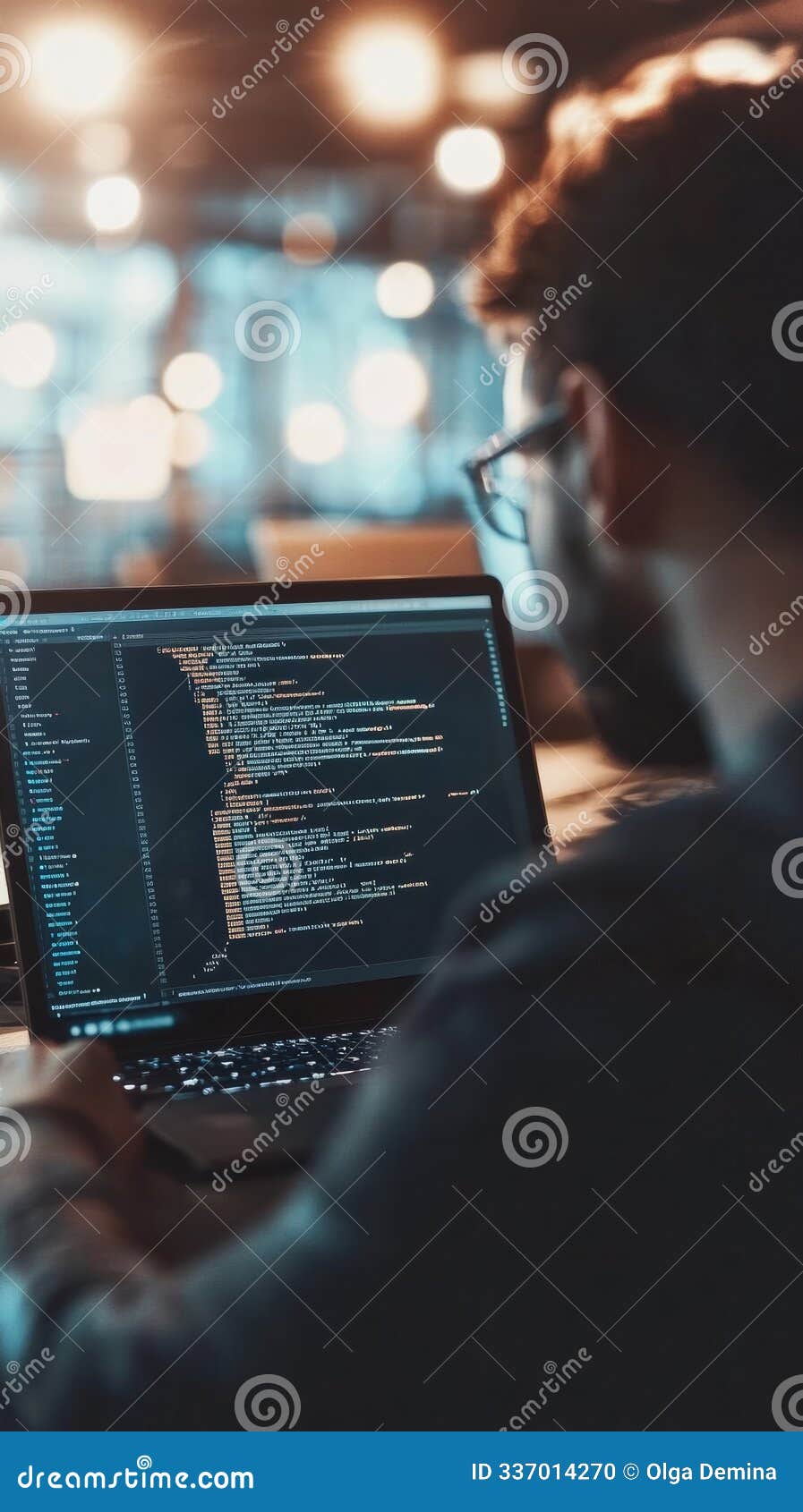 Software Developer In A Dimly Lit Workspace Coding On A Laptop With Programming Code Displayed