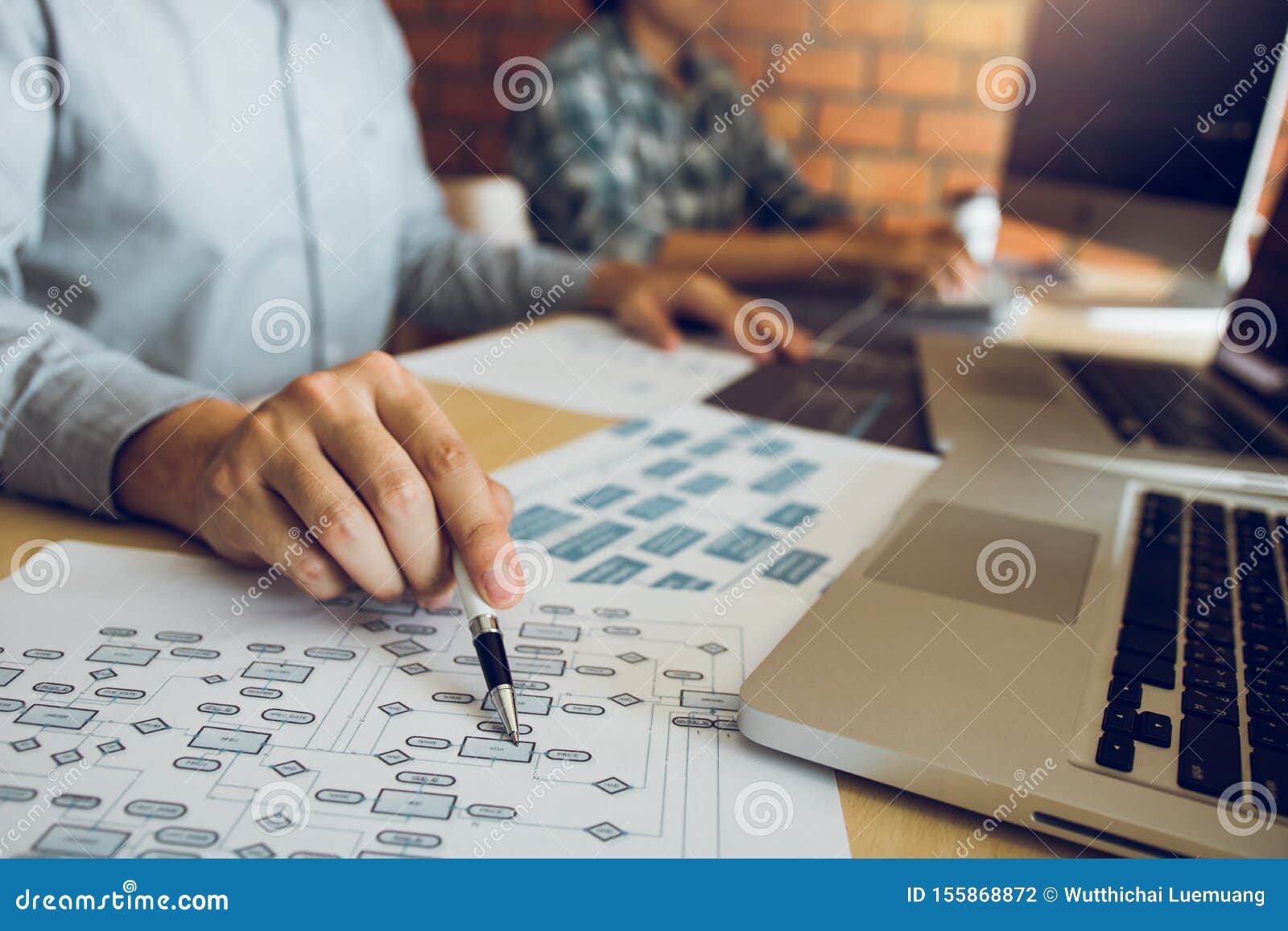 Software Developer Is Pointing To The Paper Working And Analyzing Together The Code Written Into