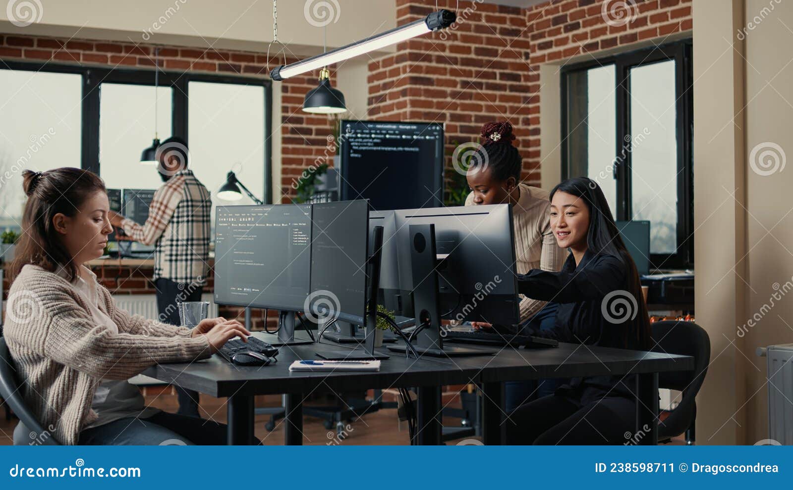 Software Engineer Typing Source Code On Computer Keyboard While Colleagues Sit Down At Desk