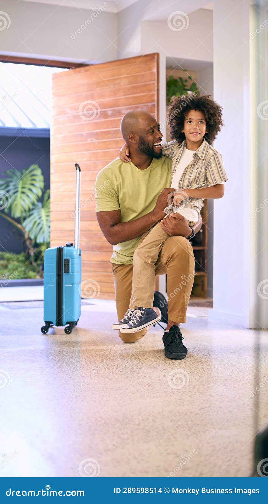 Son Greeting Father Returning Home with Luggage from Trip Away Stock ...