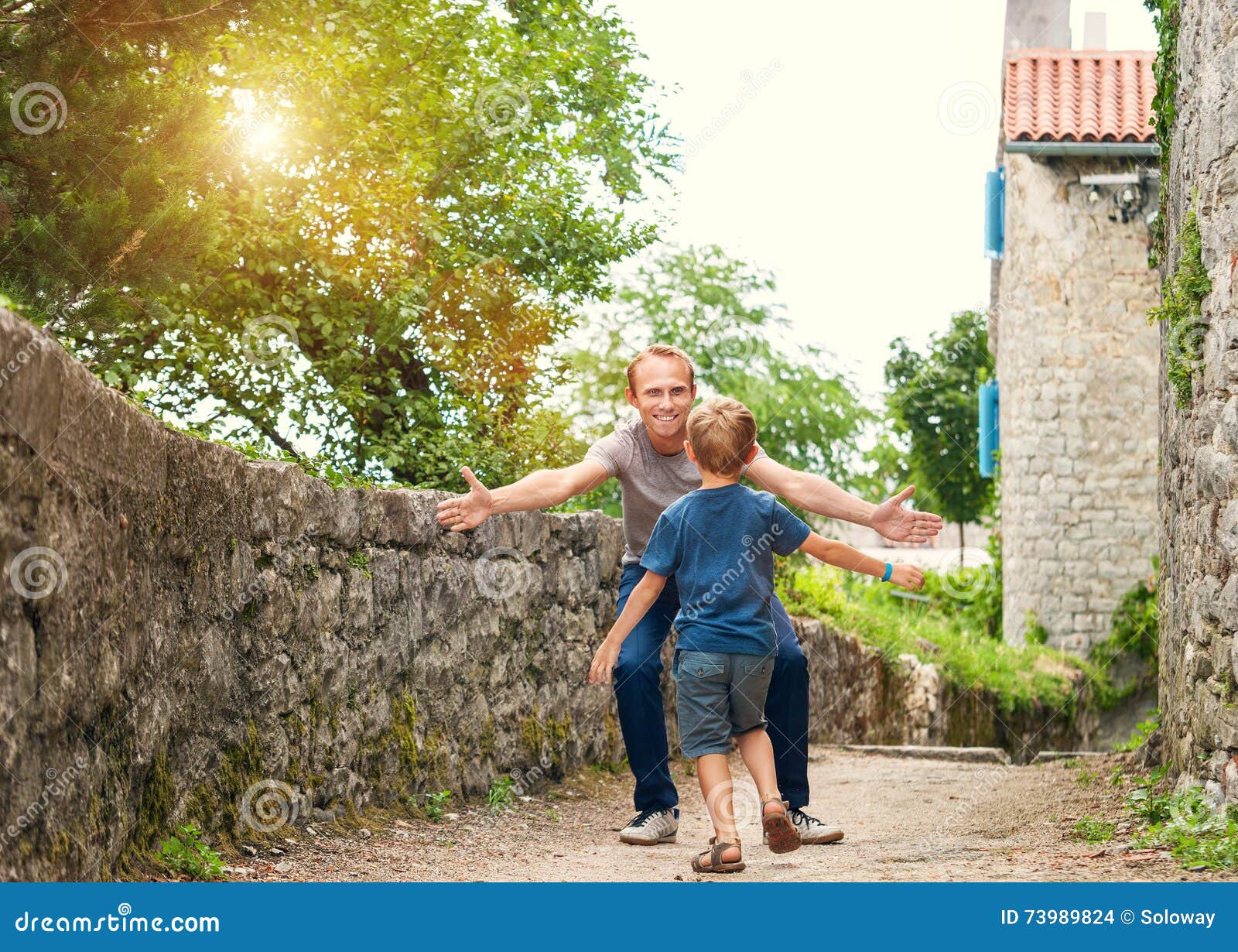 Son runs to his daddy hugs stock photo. Image of grass - 73989824