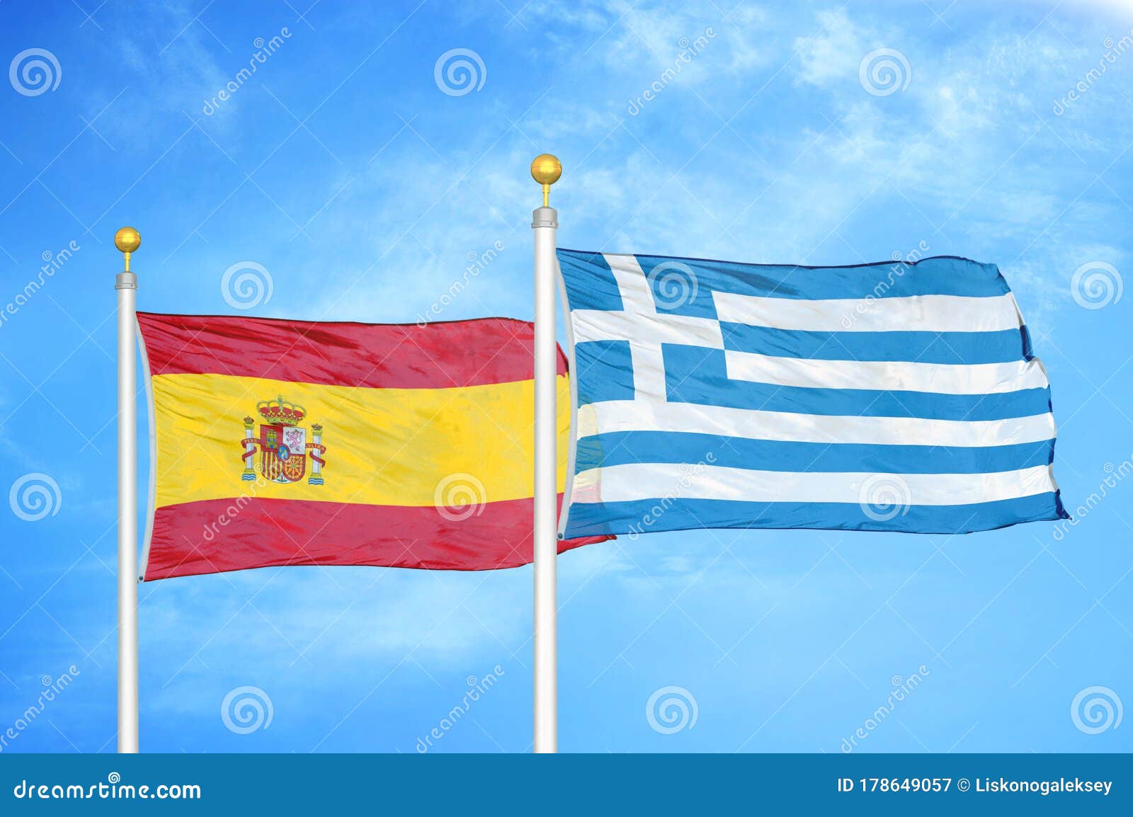 Spain and Greece Two Flags on Flagpoles and Blue Cloudy Sky Stock Image ...