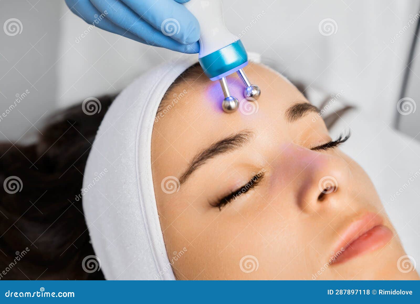 Specialist Uses Microcurrent Massage Device on Female Forehead for ...